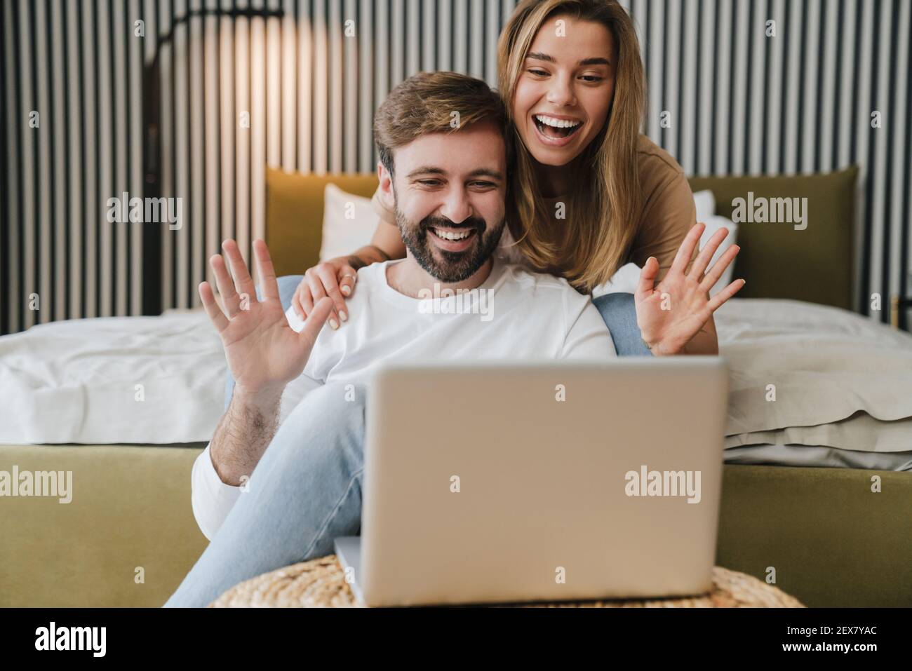 Happy young attractive couple on a video call with their friends via ...