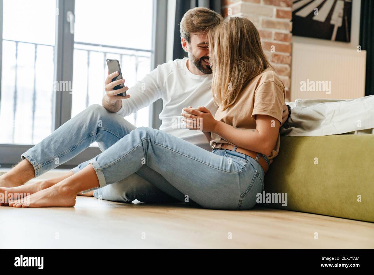 Happy beautiful couple using mobile phone while relaxing at home Stock ...