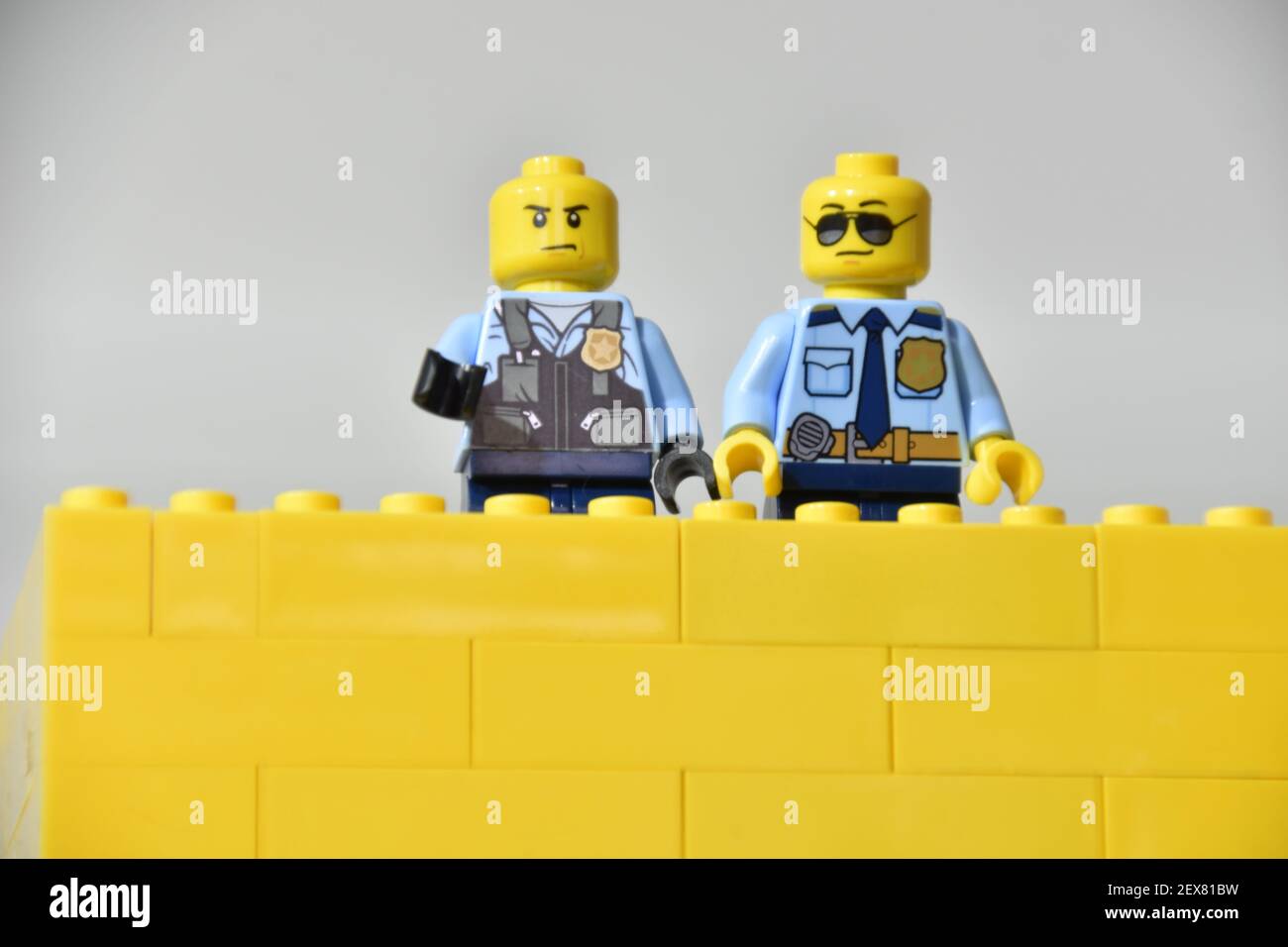 Two Policemen mini Lego figures behind a yellow brick wall built out of ...