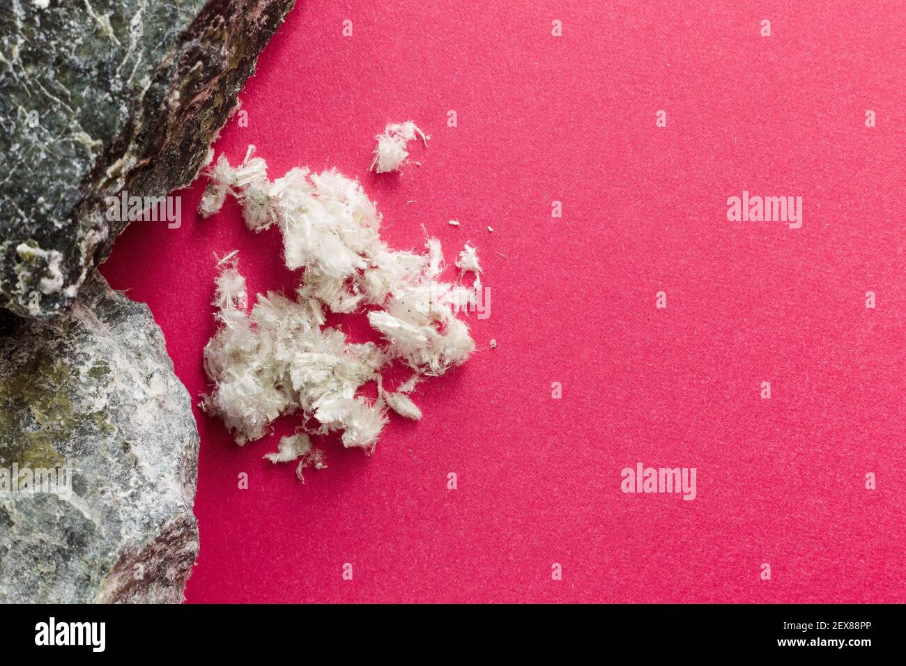 Asbestos fiber on a red background next to mineral stones. Copy space ...