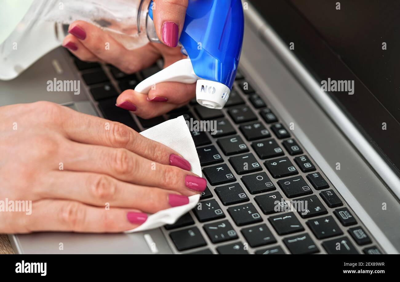 Woman cleaning laptop keyboard with white tissue, detail on her fingers ...