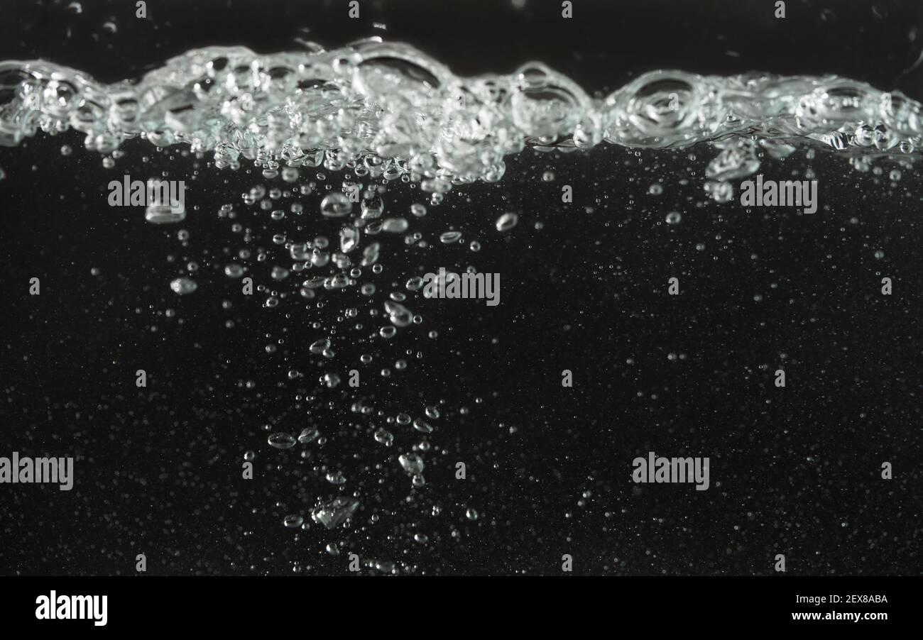 Water splashing as it's poured into aquarium tank, black background ...