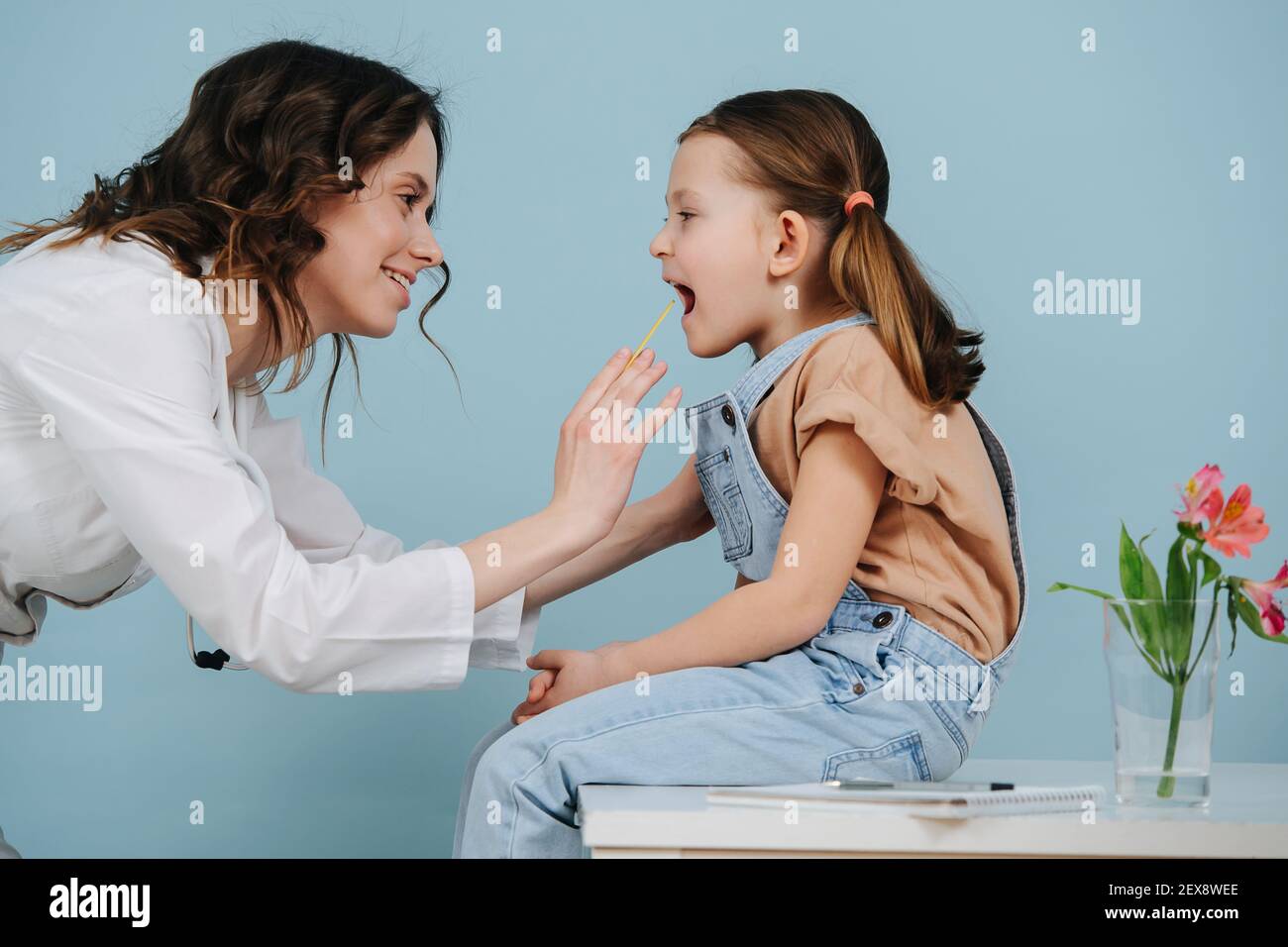 Good young female doctor examining tonsils of a happy little girl with ...