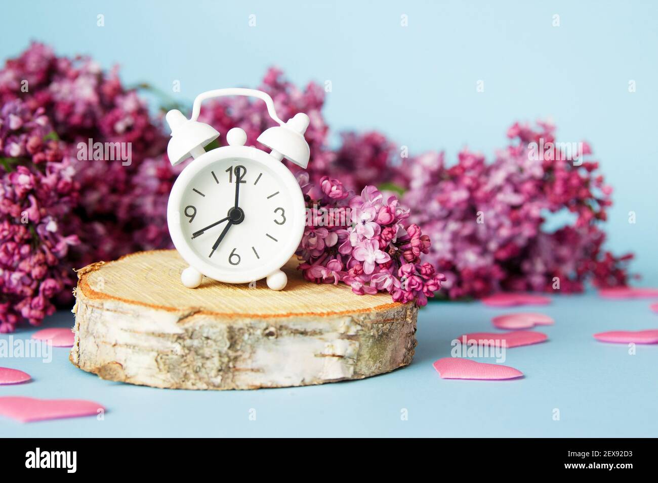 Lilac flowers with vintage tiny alarm clock on blue background. Spring ...
