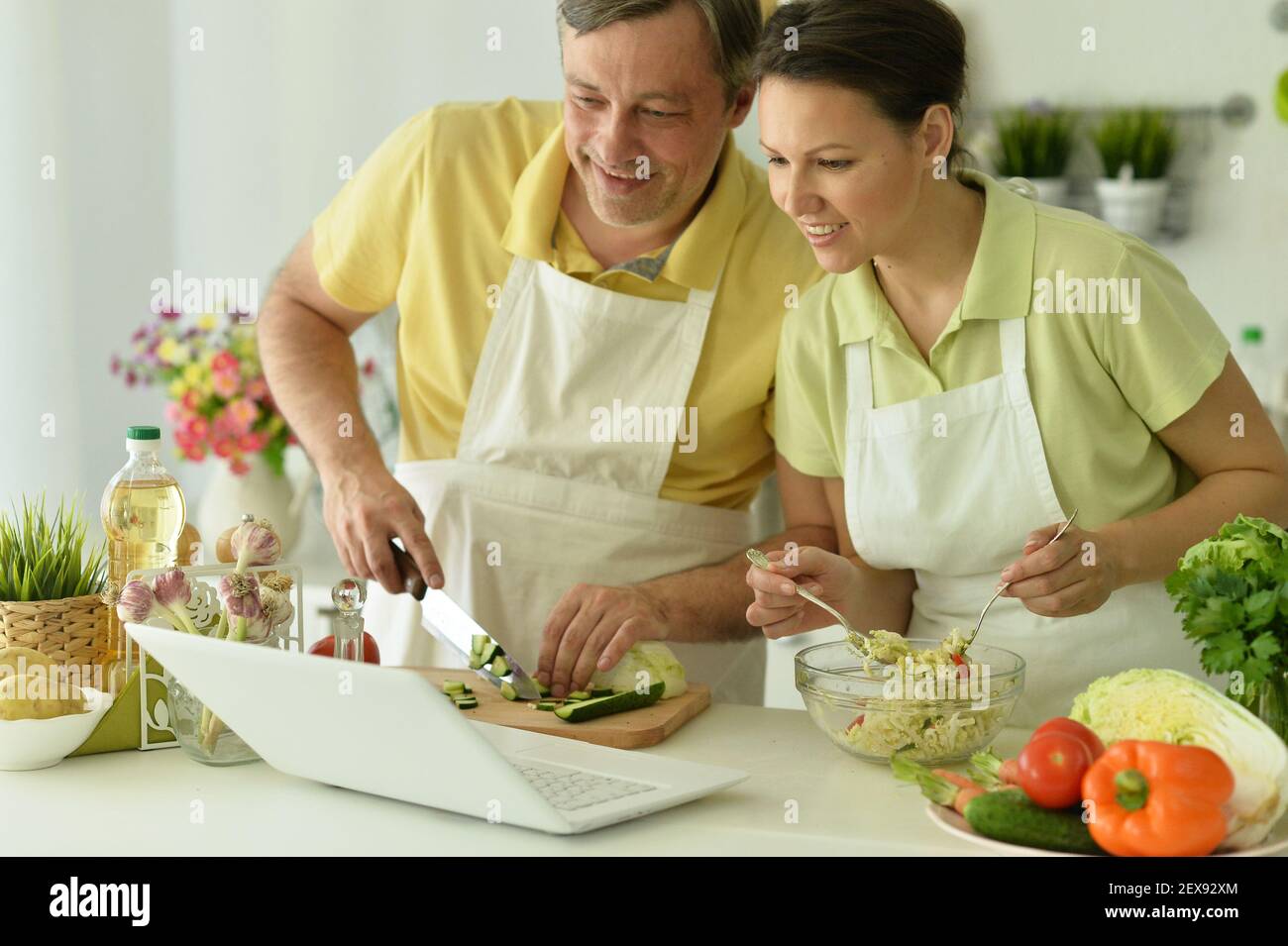 Happy husband and wife cooking together in the kitchen Stock Photo - Alamy