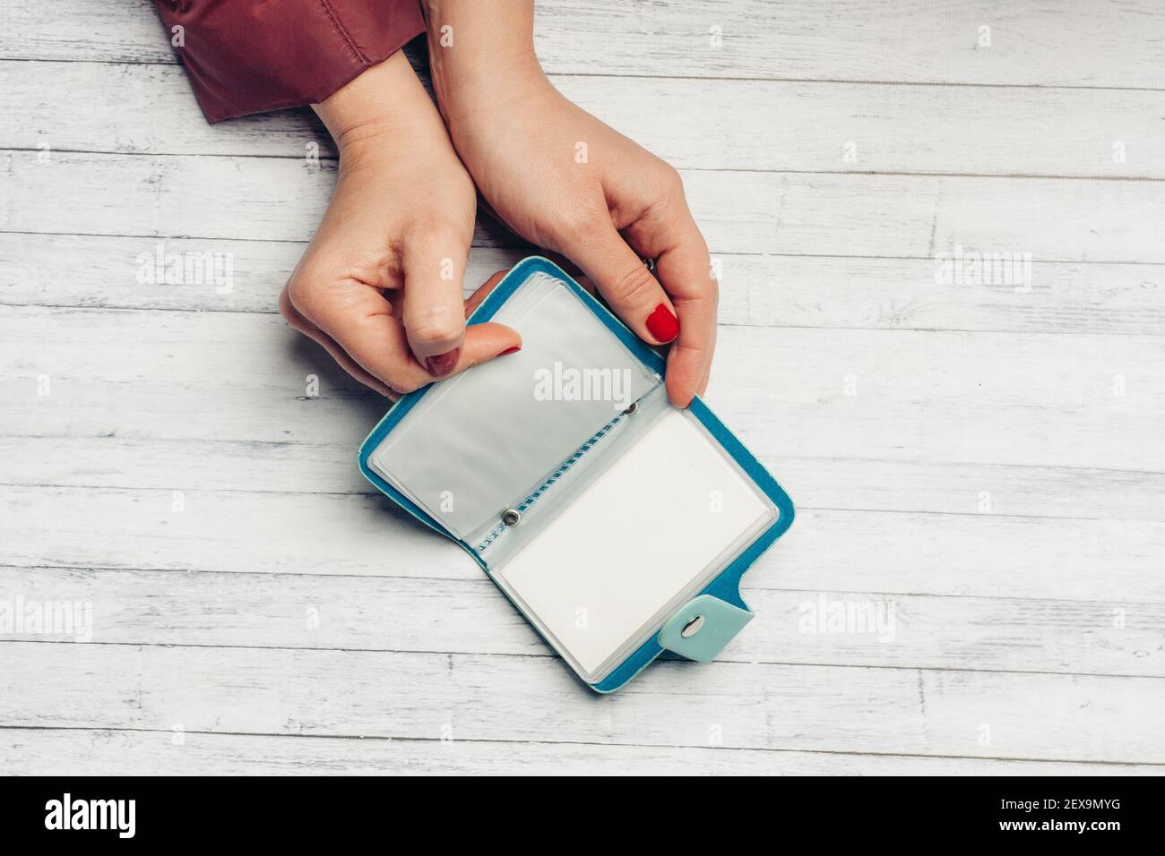 blue card holder in female hands and white sheet of paper wooden ...