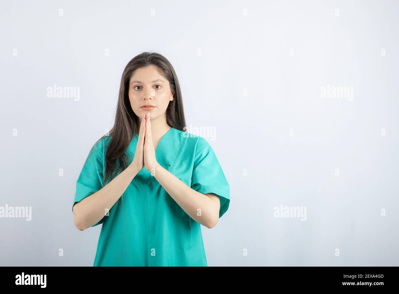 Praying young beautiful nurse looking at camera Stock Photo - Alamy
