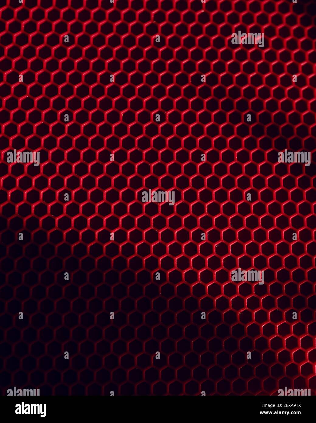 A vertical shot of red honeycomb background with light falling on it ...