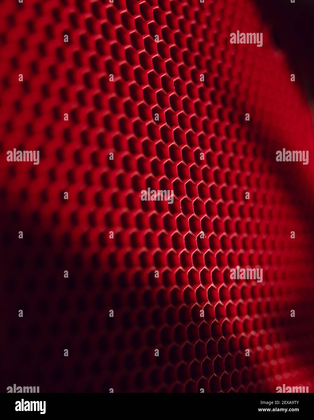 A selective focus shot of red honeycomb background with light falling ...