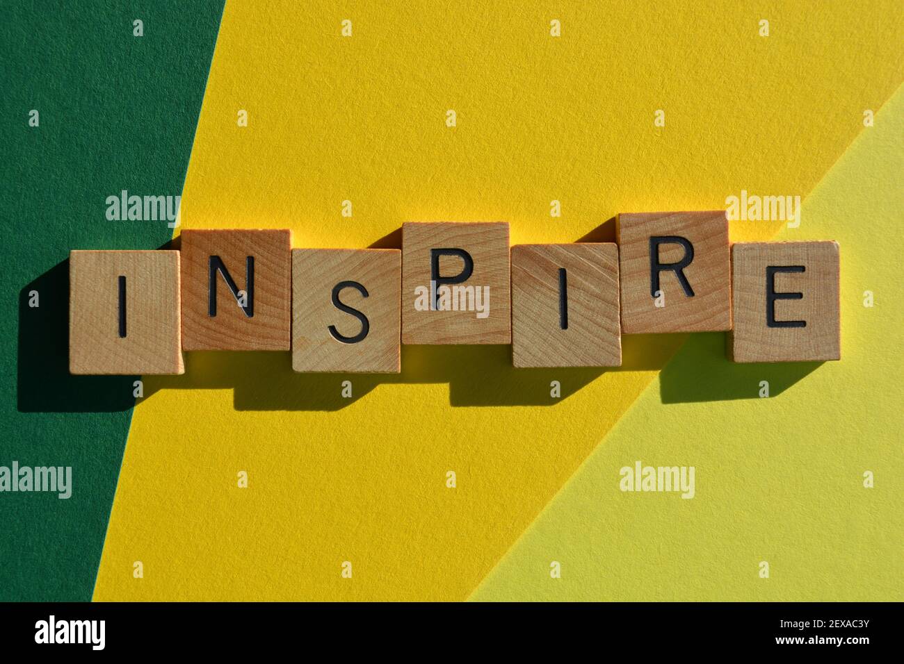 Inspire, word in wooden alphabet letters isolated on yellow and green ...
