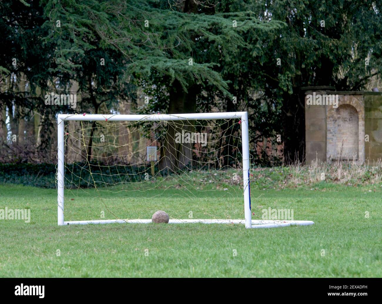 Small 5 a side goal posts with a ball on the ground with trees in the ...