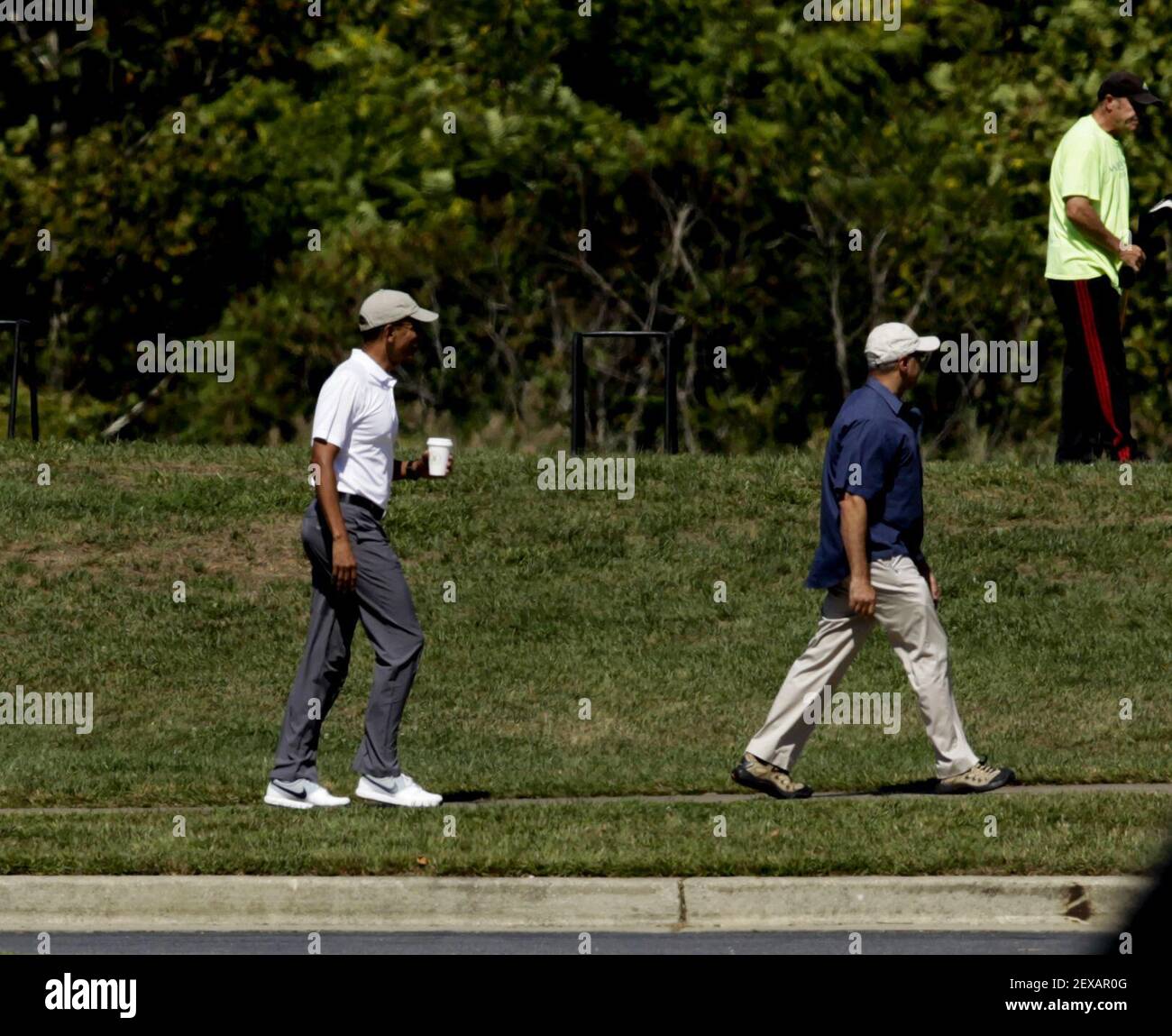US President Barack Obama walks holding a cup of coffee before playing ...