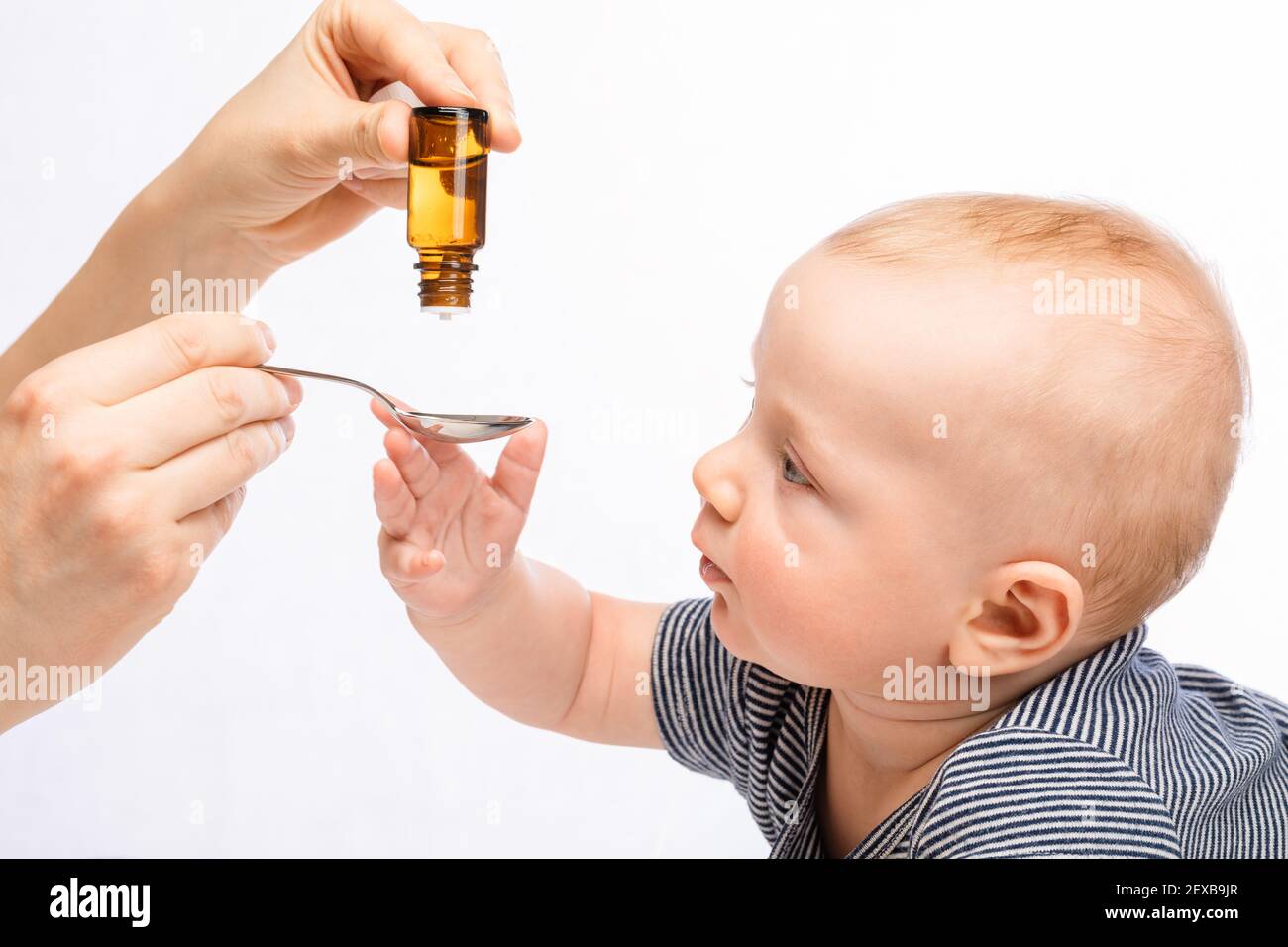 Mother feeding baby boy with drop of vitamin or liquid medicine from ...
