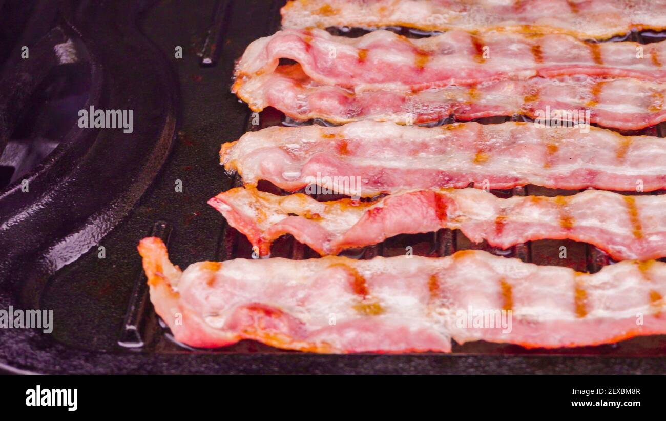 Cooking bacon stips on an outdoor gas grill Stock Photo - Alamy