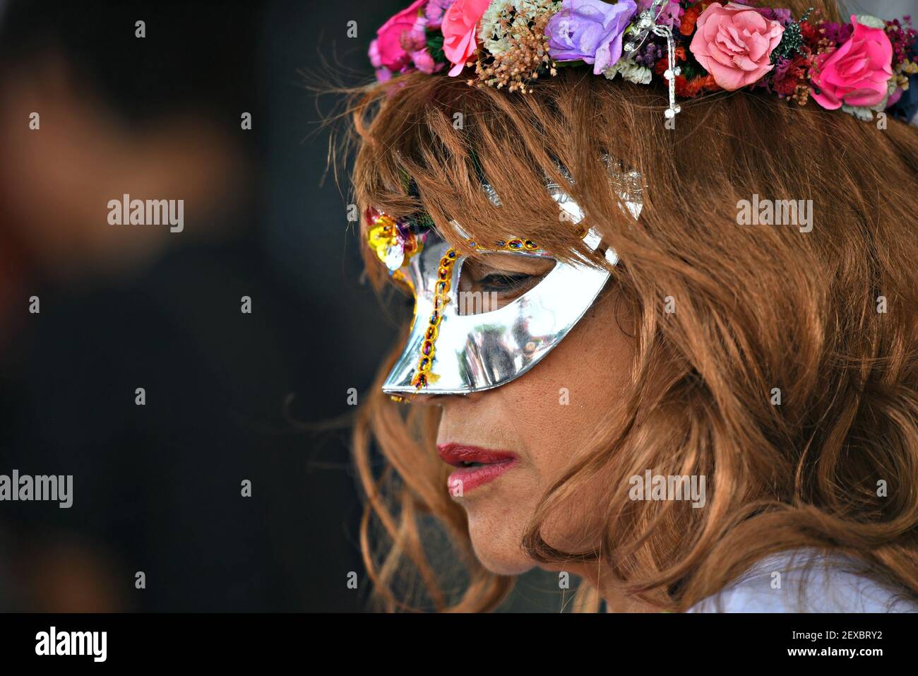 Young woman with a disguise mask and a flower wreath participating at ...