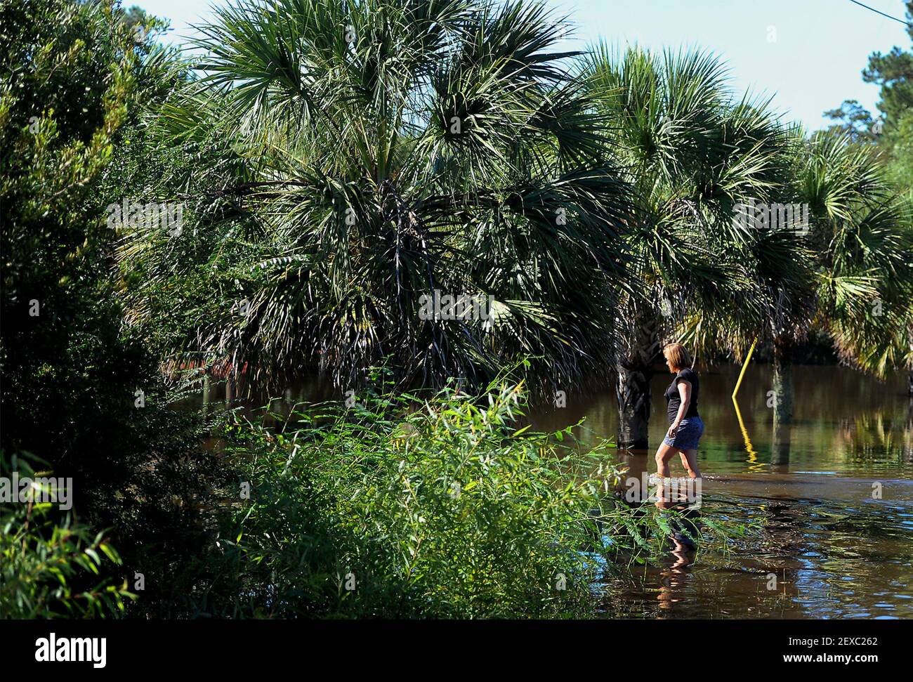 Cindy O'Neill, right, walks through standing water back to her home off ...