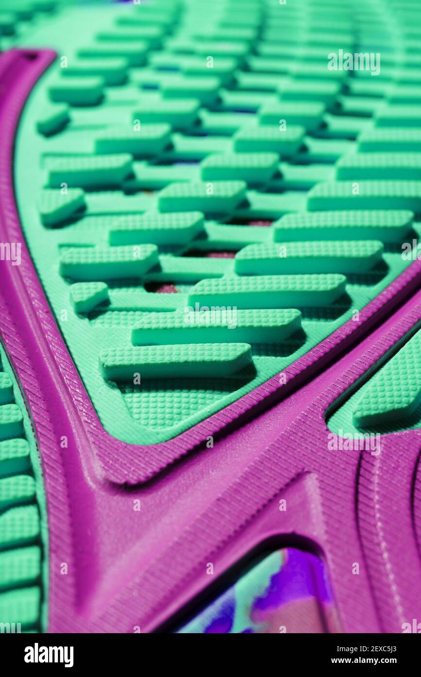 A sporty running shoe with a textured green sole on a black background ...