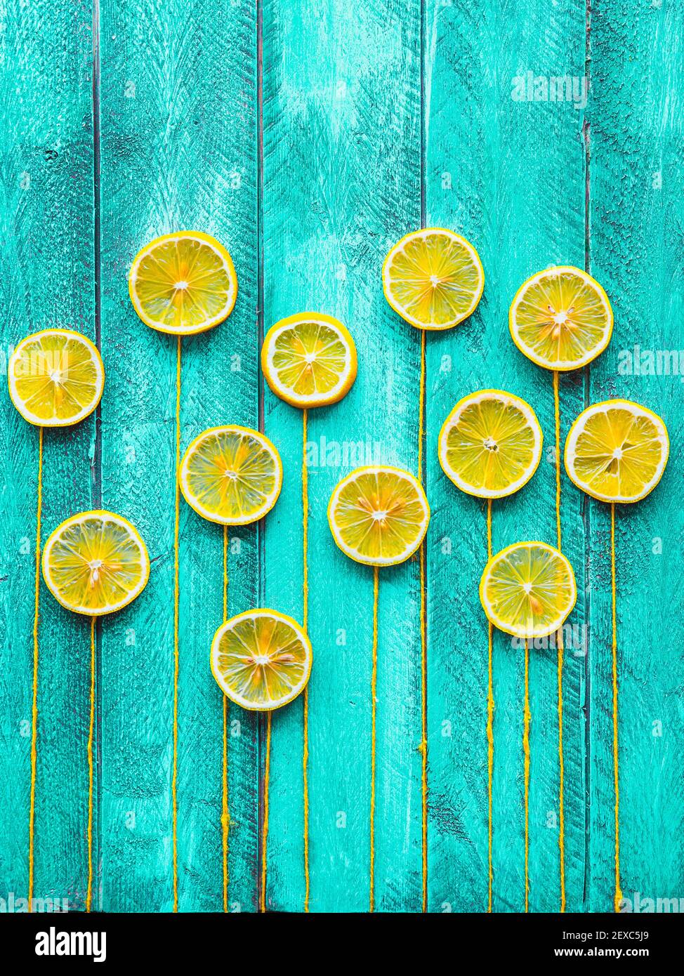 Conceptual arrangement of lemon slices and yellow string on a blue ...
