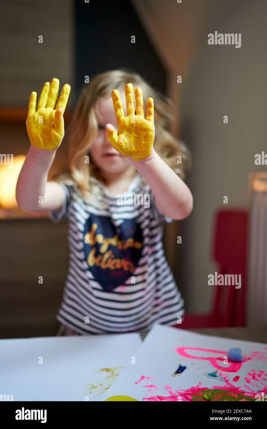 Cute little artist girl showing yellow painted palms to the camera with mother a side Stock ...