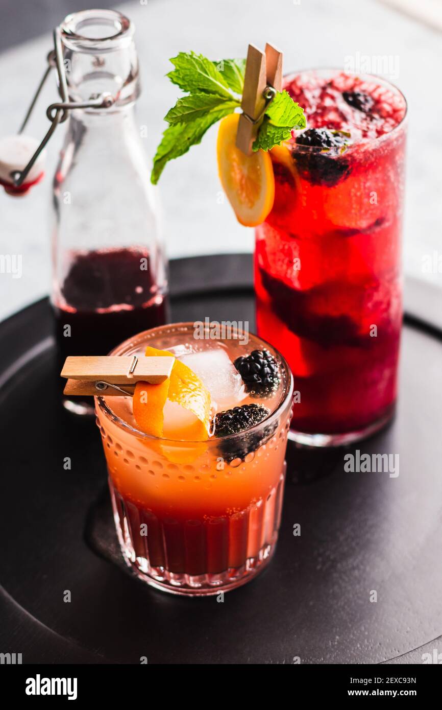 Orange and red cocktails garnished with blackberries, lemon, & mint ...