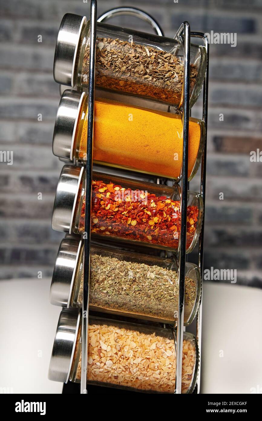 A metal spice rack with many glass bottles filled with different spices ...