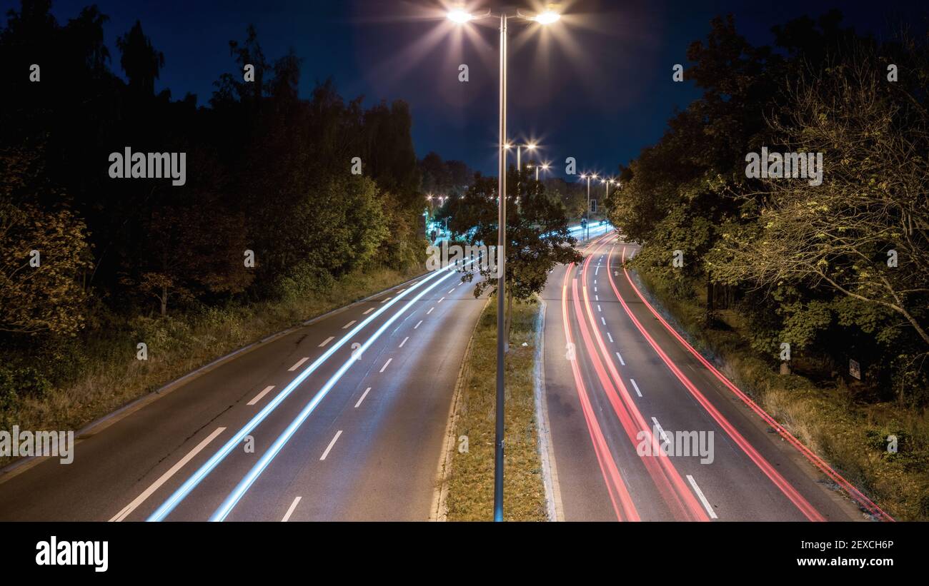 A long exposure shot of a four-lane road at night with glowing vehicle ...