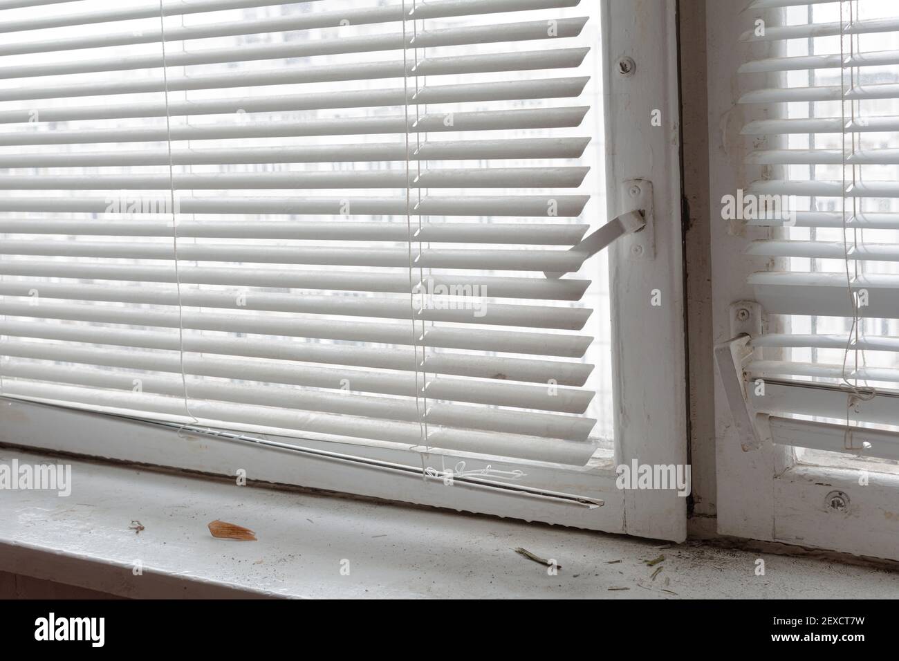 Wooden window and white horizontal blinds. A fragment of an old wooden ...