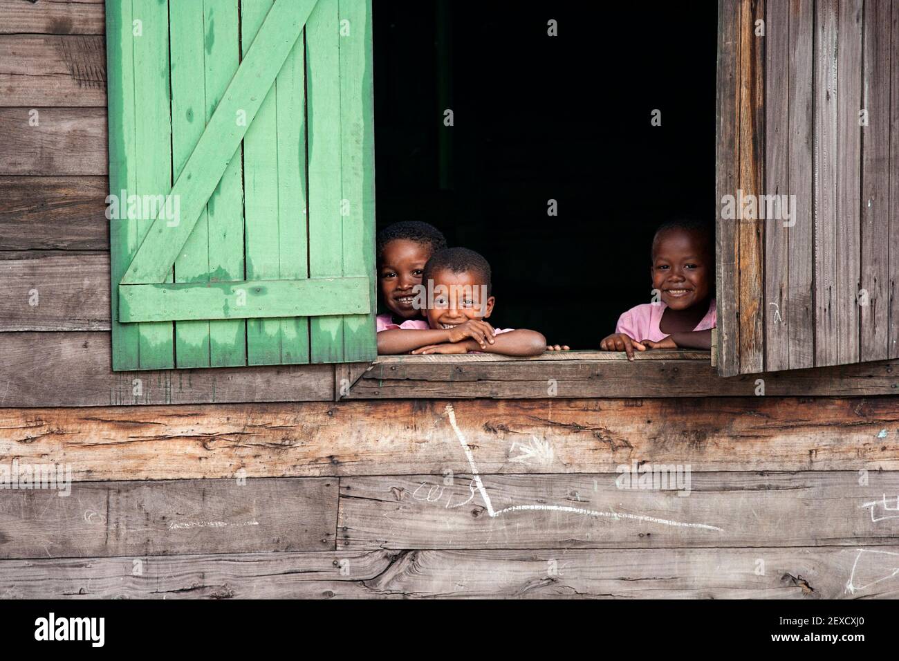 Kids in school uniforms smiling through window in the local school in ...