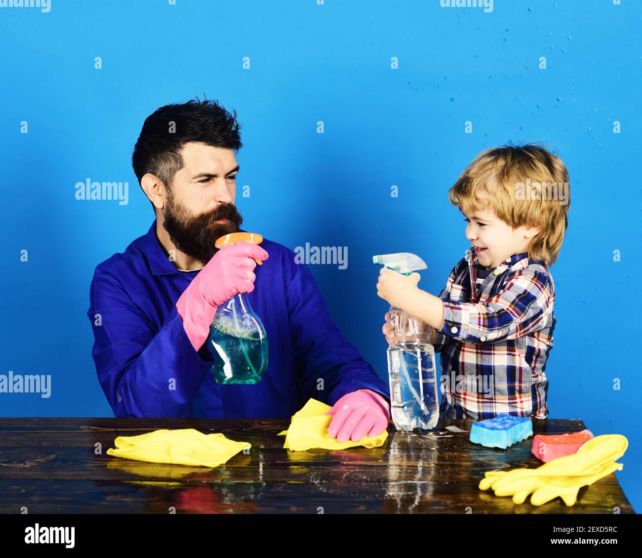 Dad and son plays with cleaning props on blue background. Kid with ...