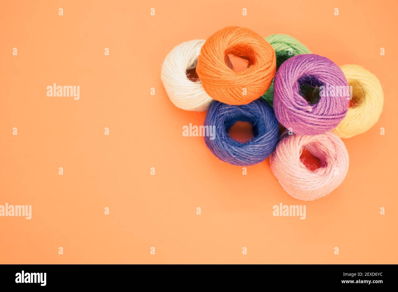 A stack of multi-colored yarn balls in the orange background with copy ...