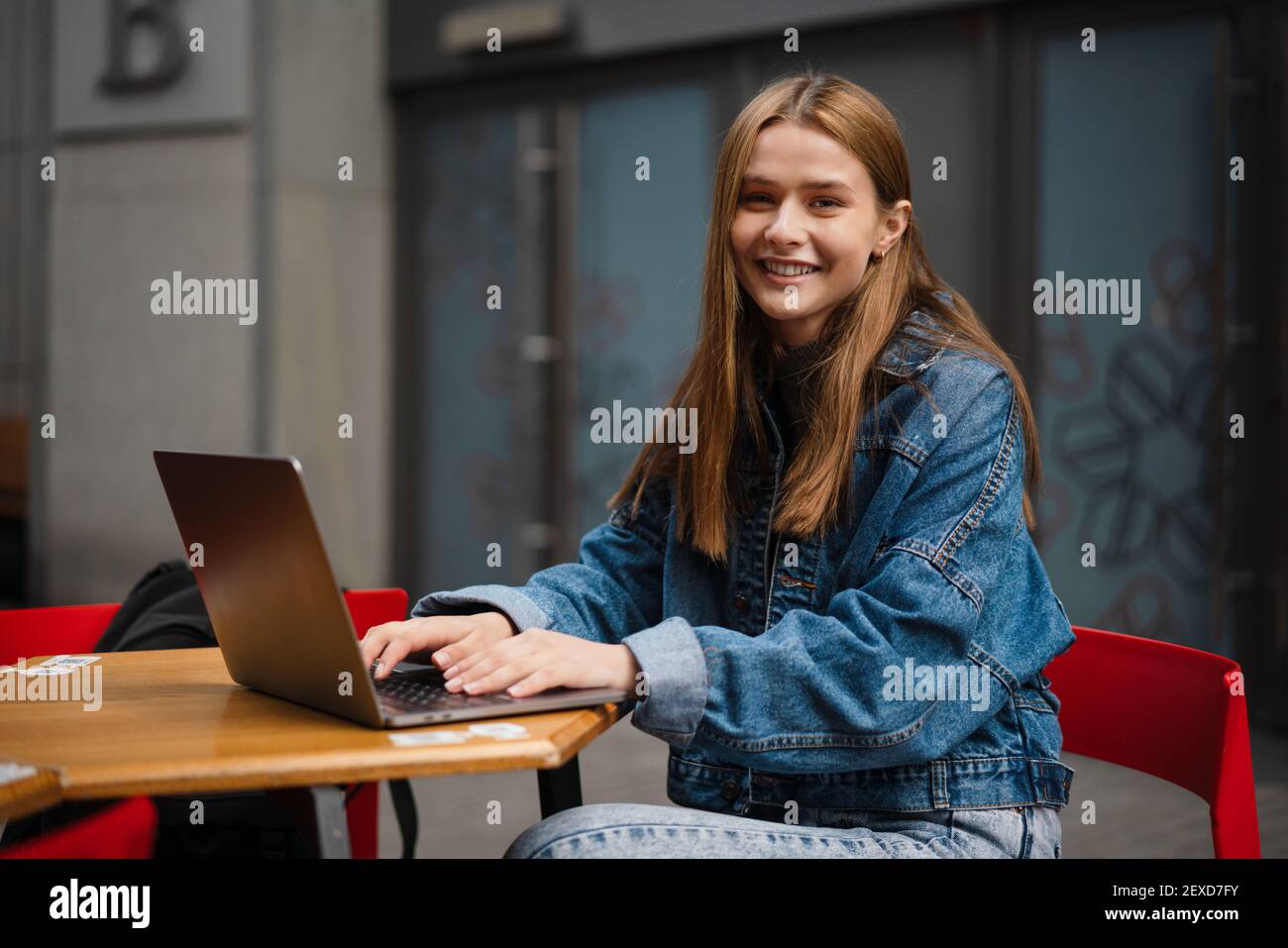 Beautiful happy student girl working with laptop while sitting in ...