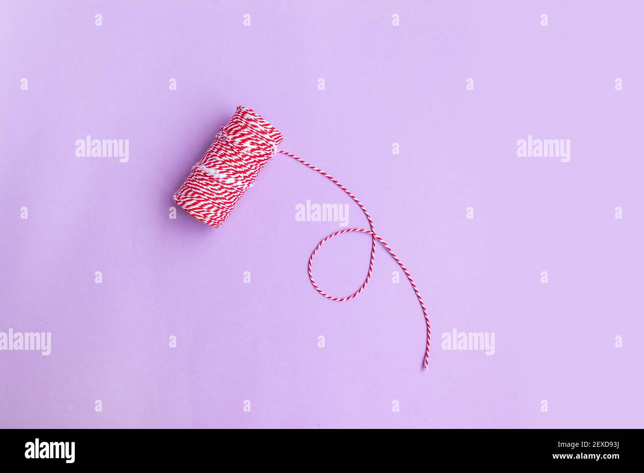 Red and white rope reel on solid purple background with copy space, top ...