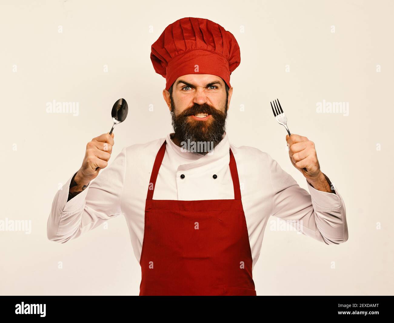 Man with beard holds fork and spoon on white background. Cook with mad ...