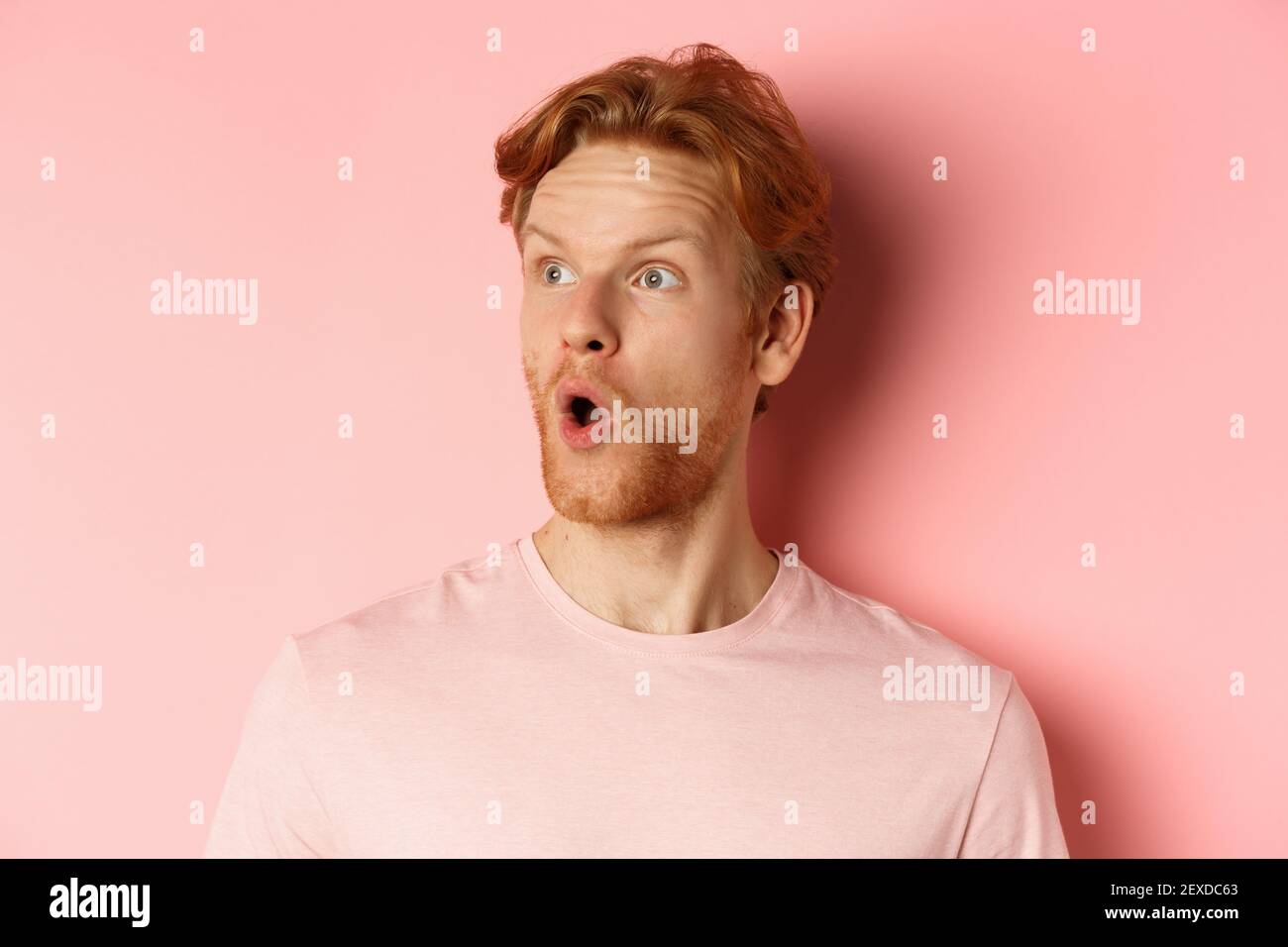 Close up of shocked redhead man with beard, saying wow, looking left ...