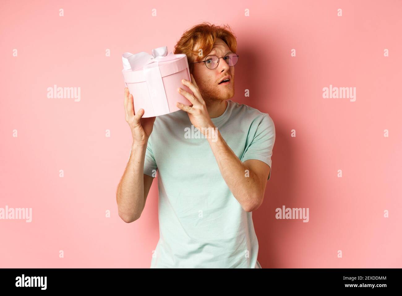 Valentines day and romance concept. Handsome redhead man shaking gift ...