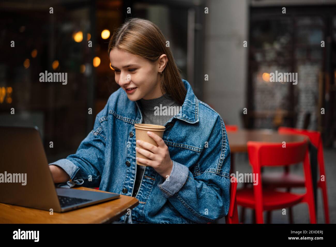 Beautiful smiling student girl drinking coffee while working with ...