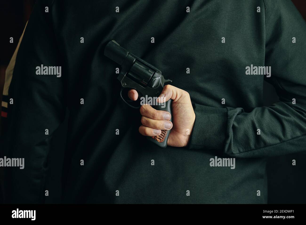 Man in dark clothes with revolver on his back. Person holds firearm for ...