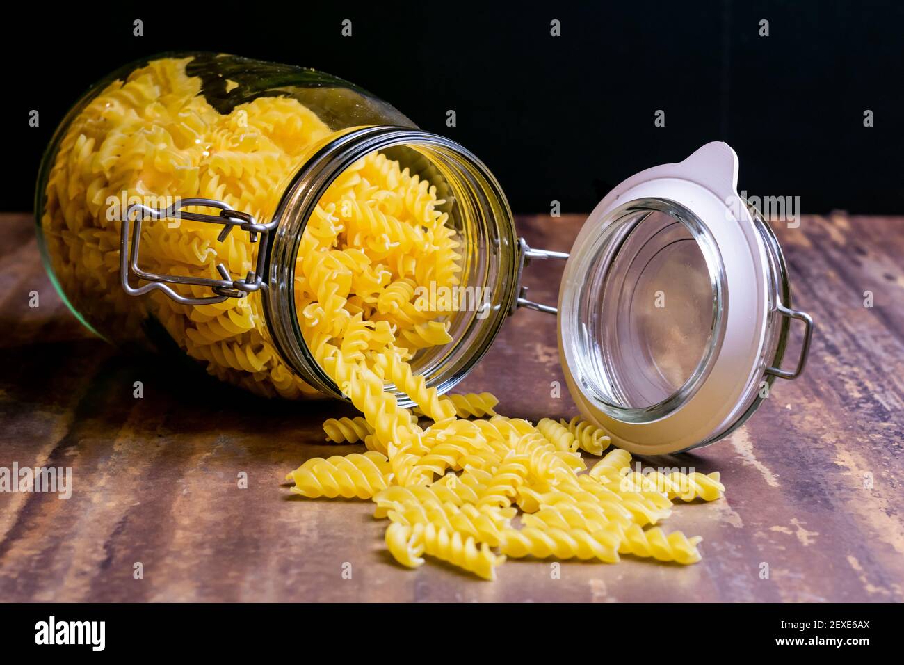 Fussili pasta falling out from a big air tight glass jar. Raw dry pasta ...