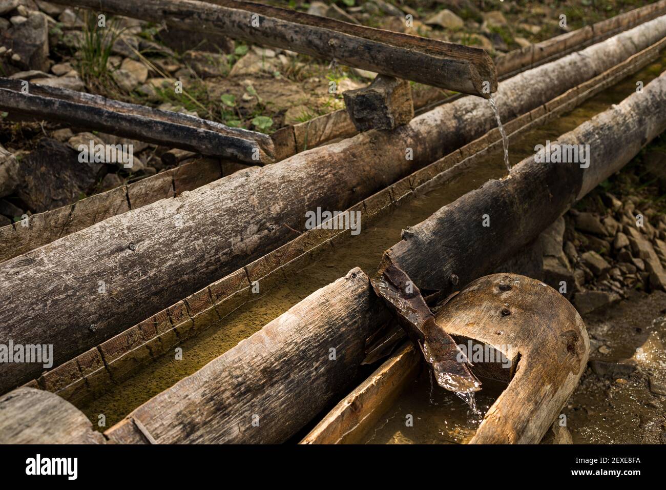 A closeup of a wooden made faucet with water dripping into the wooden ...