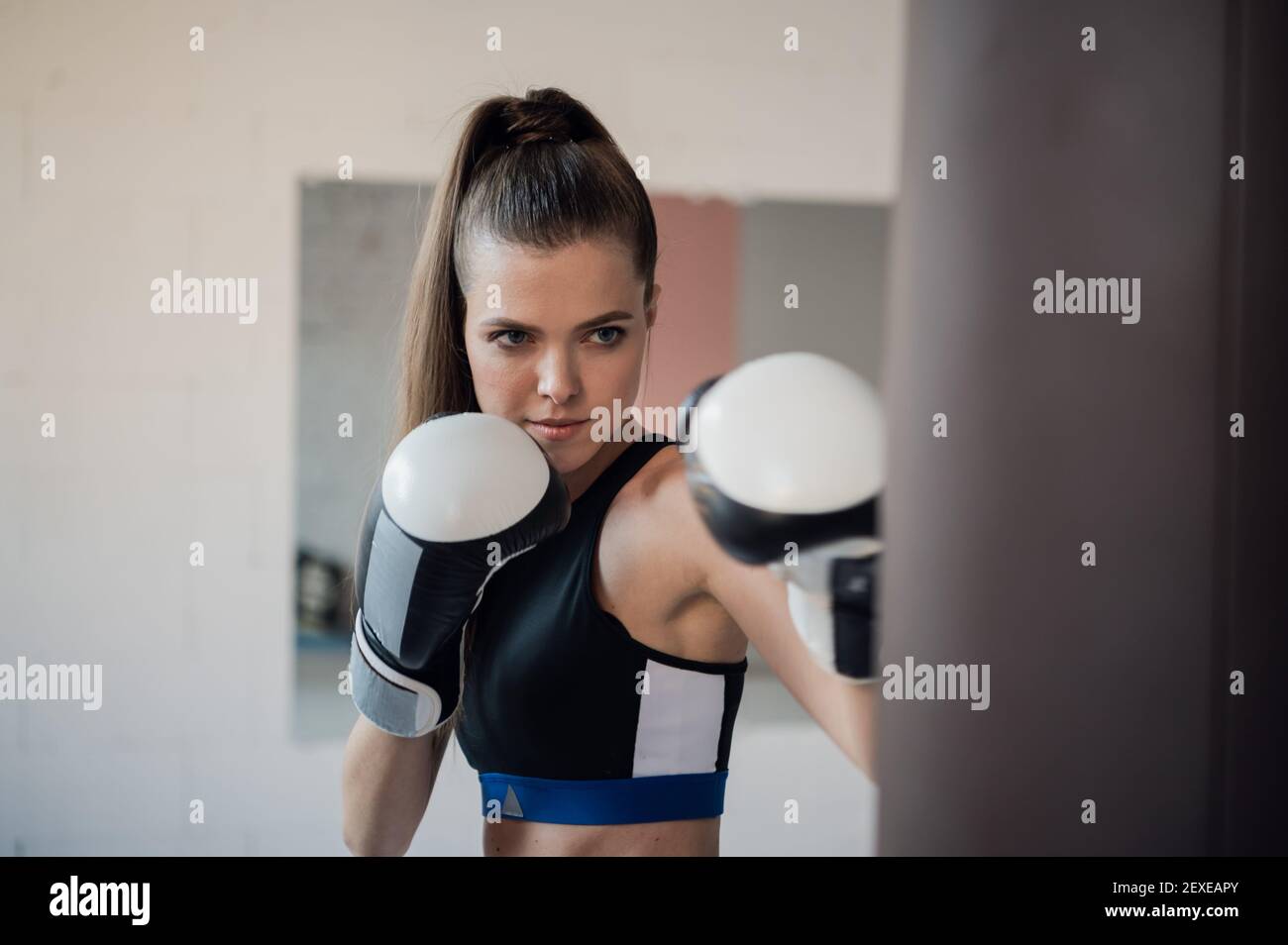 Female athlete boxing the punching bag in urban industrial gym Stock ...