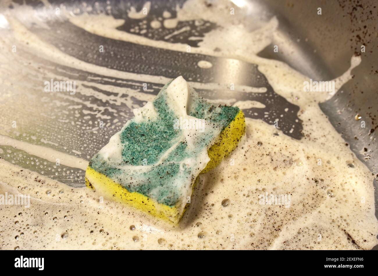 Sponge with detergent and foam while washing the sink in the kitchen ...