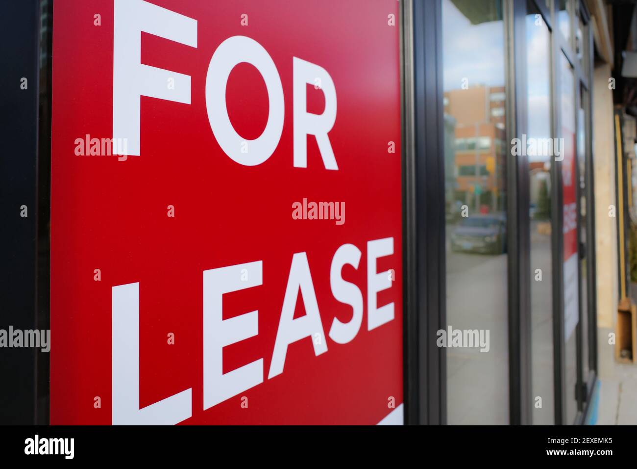 A red and white 'for lease' sign hangs in the window of a storefront ...