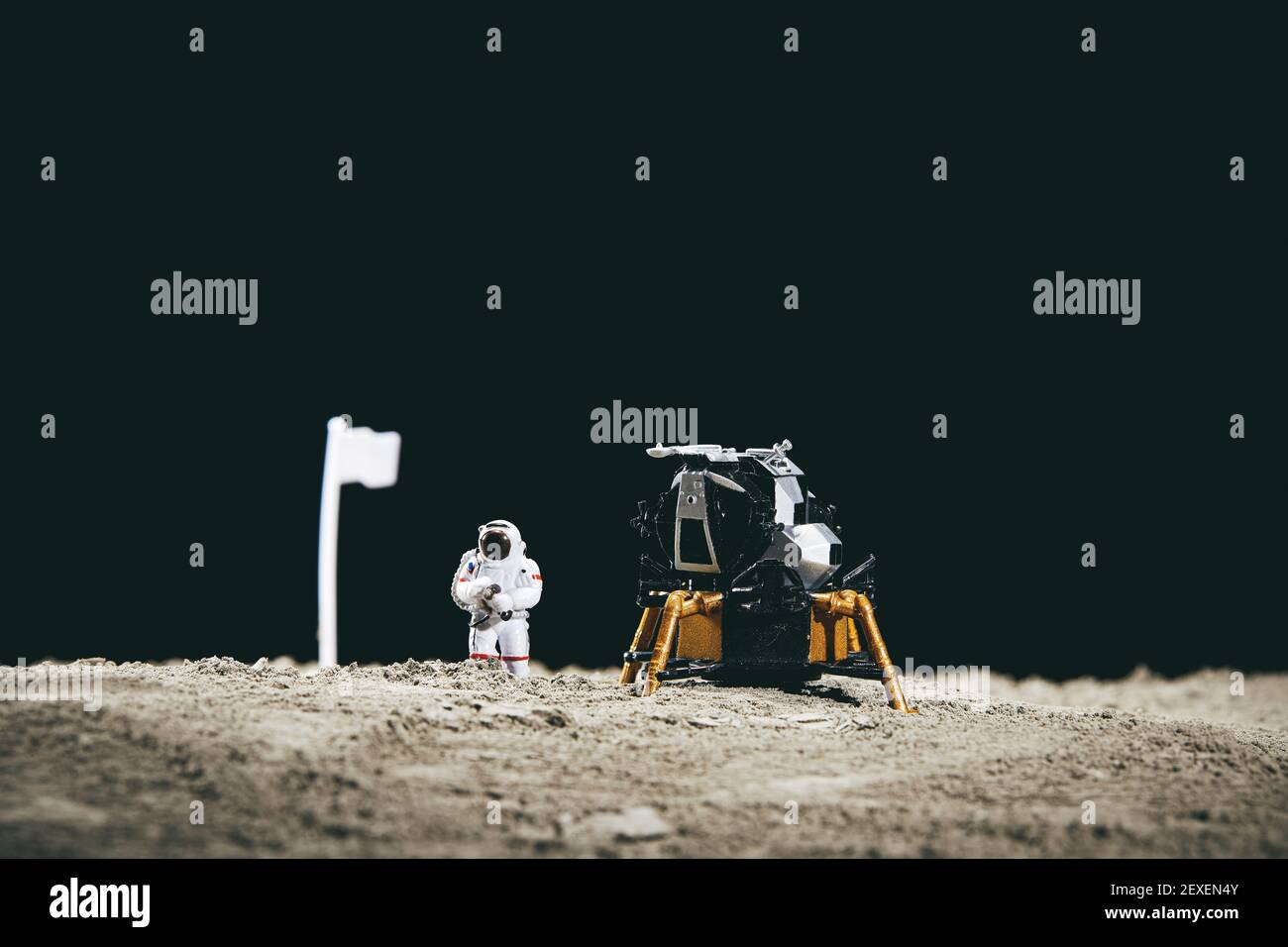 An astronaut miniature toy in the middle of the flag and spaceship on ...