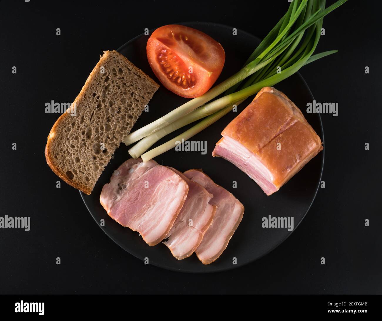 Food, lard, green onions, tomato, black bread, on a black plate, on a ...
