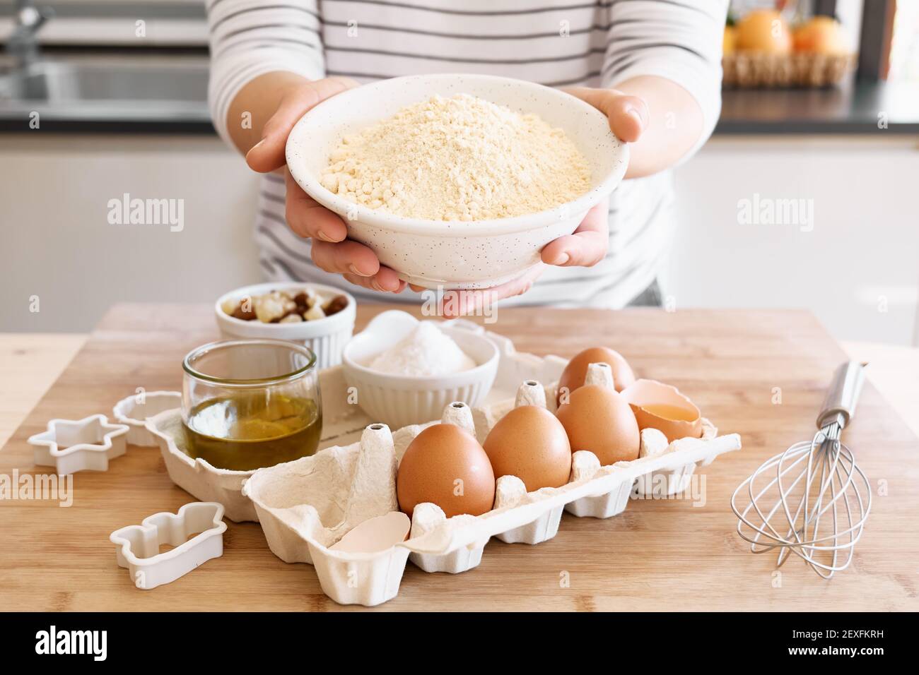 Woman holds a white bowl with chickpea flour over table with ...