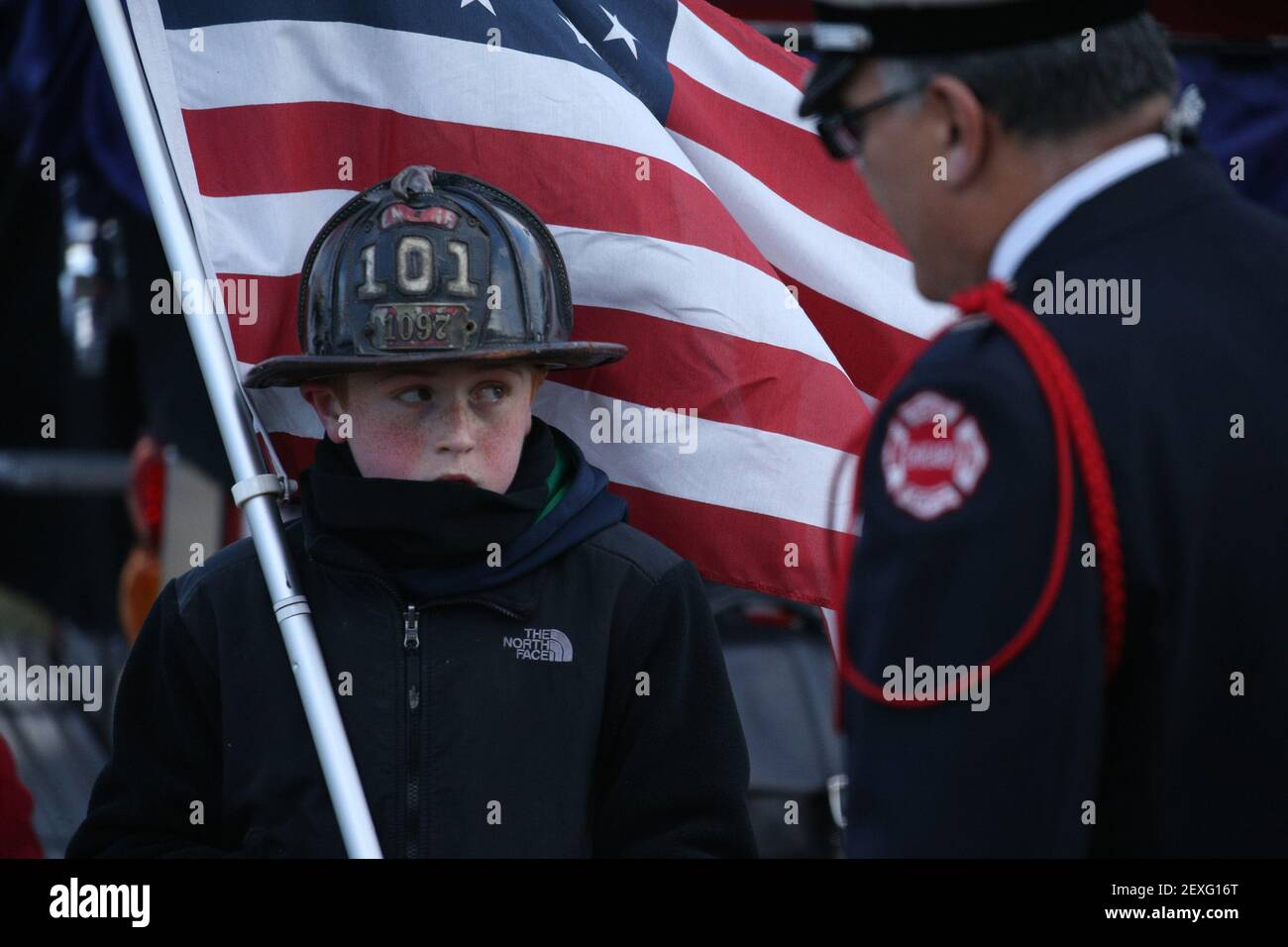 A boy wears a helmet and carries a flag outside Chicago firefighter ...