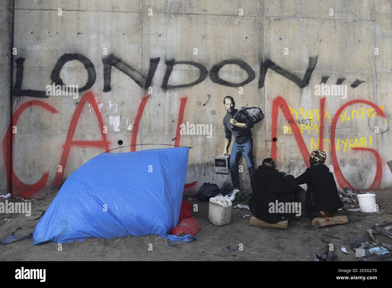 Two refugees sitting near Banksy's latest graffiti, at the Jungle camp ...
