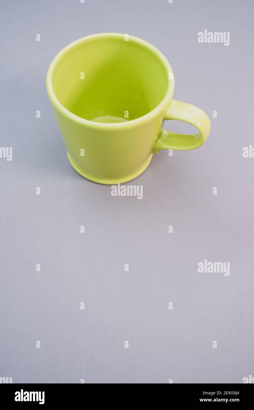 A vertical shot of an empty green plastic cup isolated on a grey ...