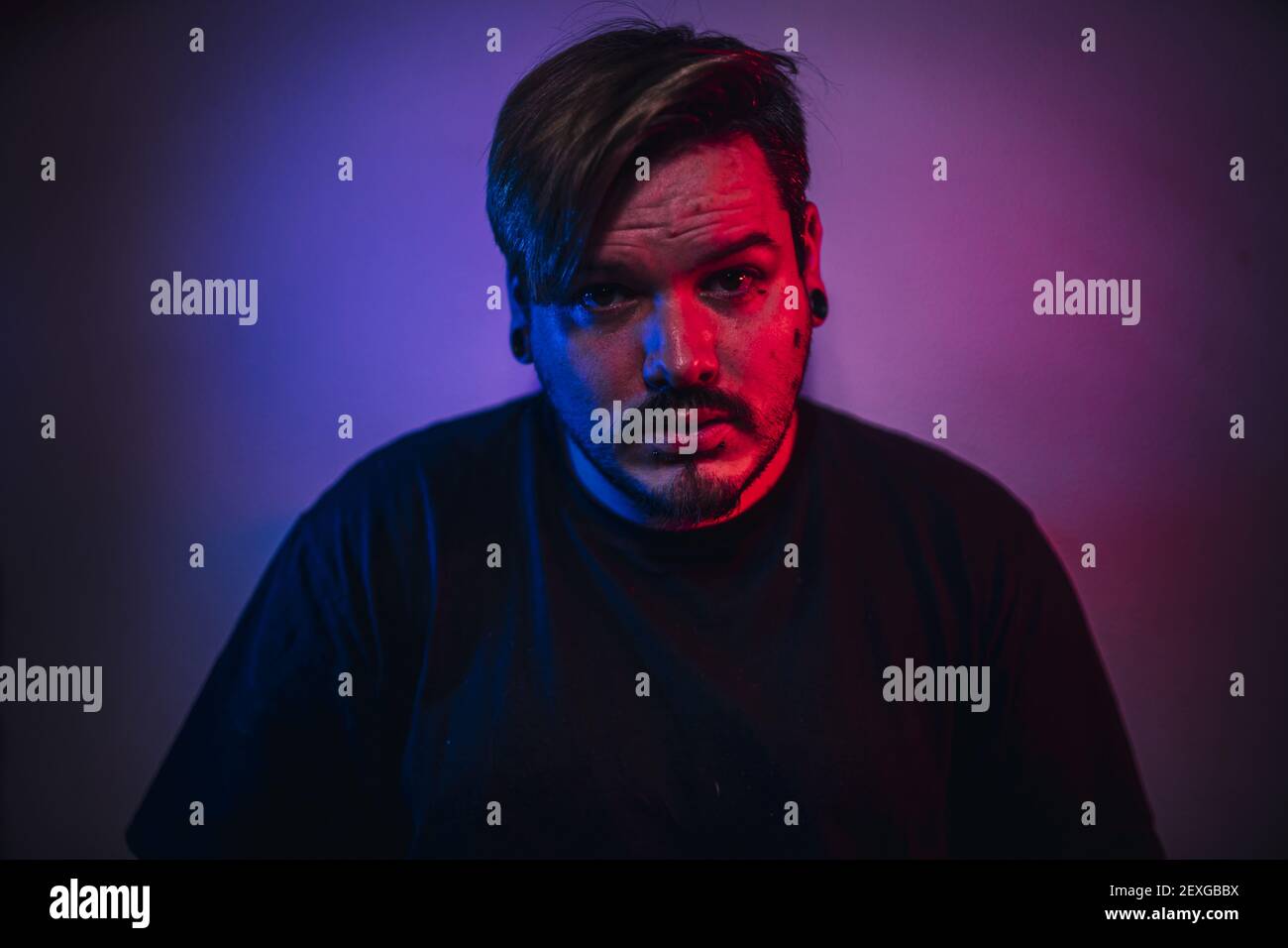 A portrait of an adult male with a beard and earlobe earrings under ...