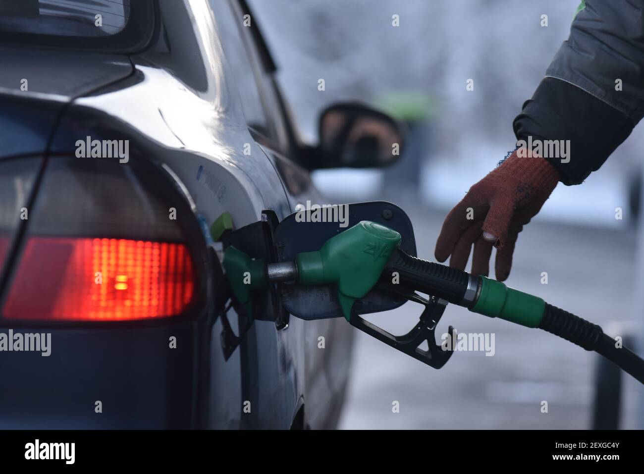 A pump attendant puts a fuel pipe into a car for re-fueling at a gas ...